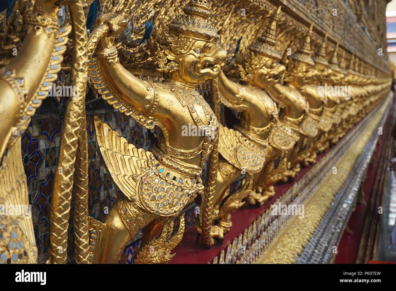 Row of identical golden Garuda statues recede into the distance on the ...