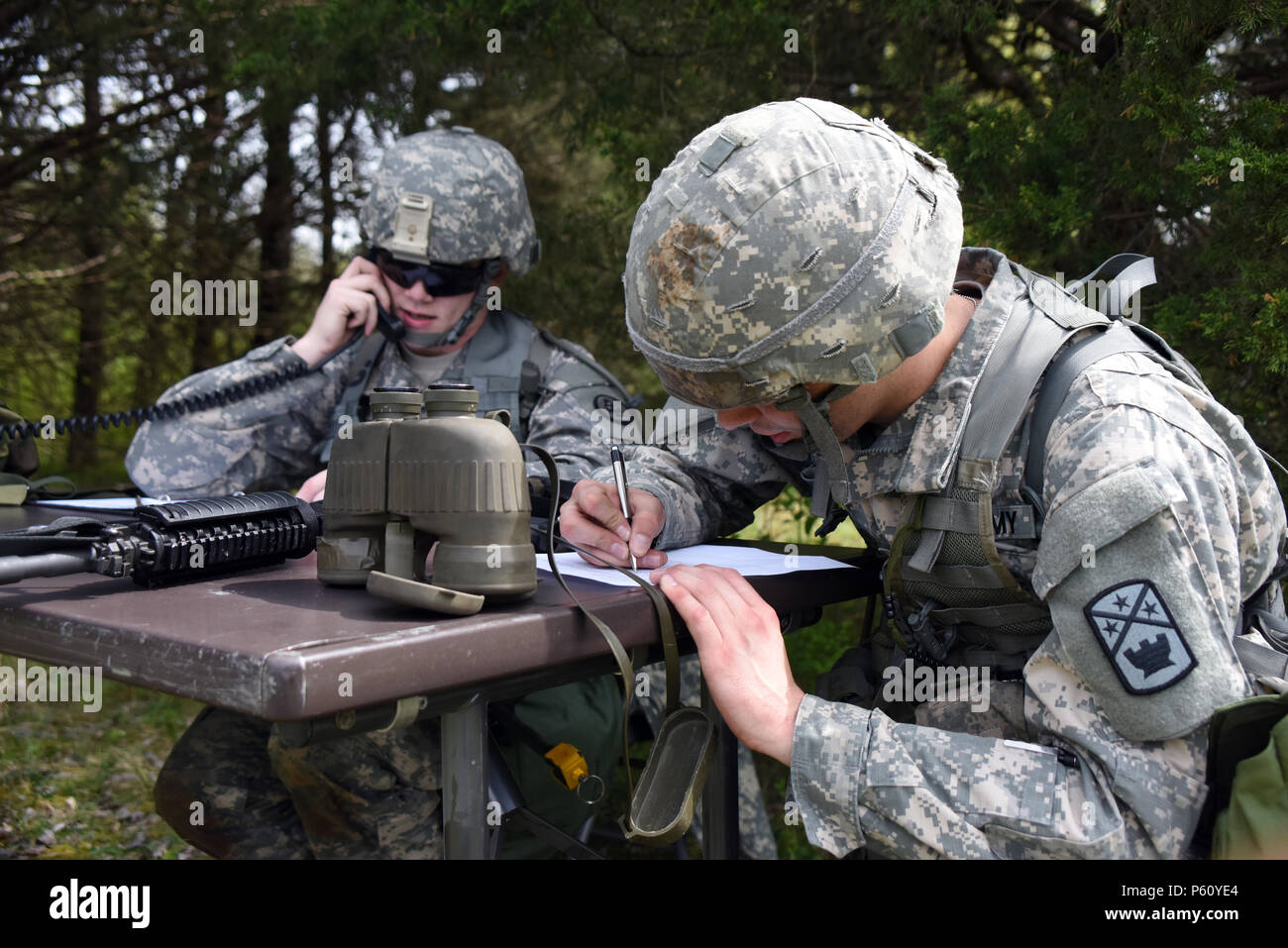 A Soldier locates a point on a map while another Soldier radios that ...