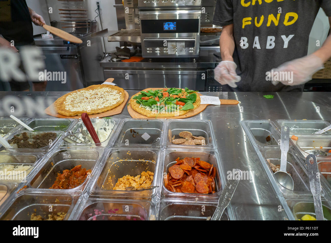 New York, USA, 27 June 2018. Employees construct a pizza right before ...