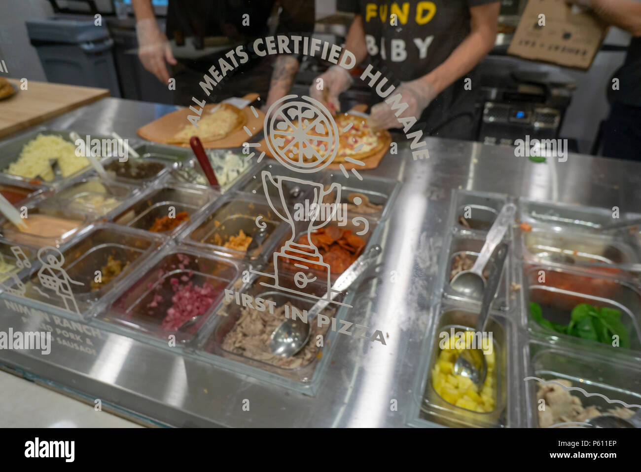 New York, USA, 27 June 2018. Employees construct a pizza right before ...