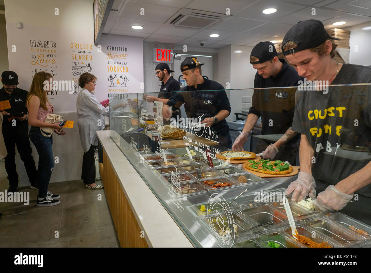 New York, USA, 27 June 2018. Employees construct a pizza right before ...
