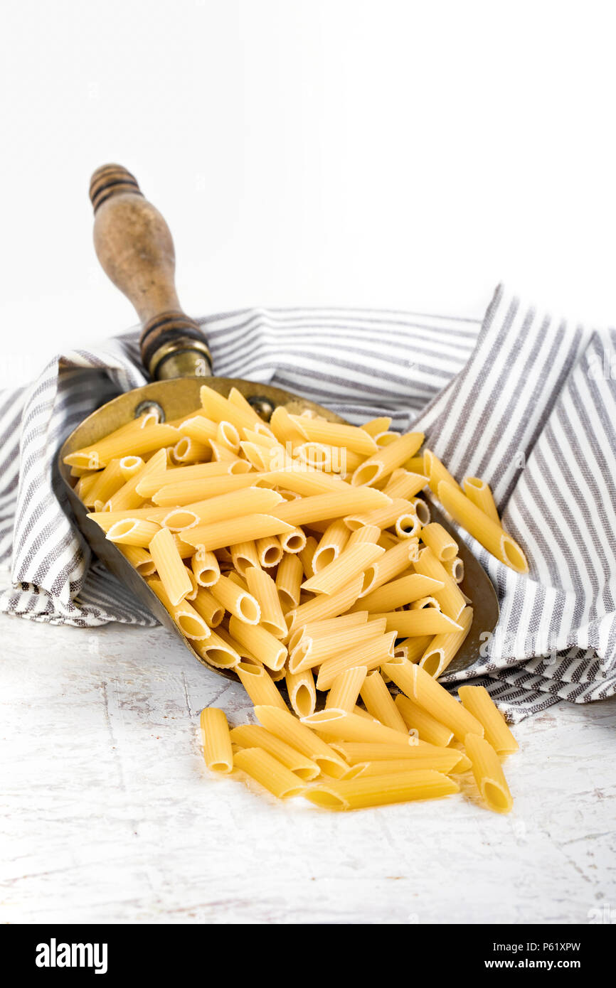 Raw pasta type penne rigate in copper bailer, on white background Stock ...