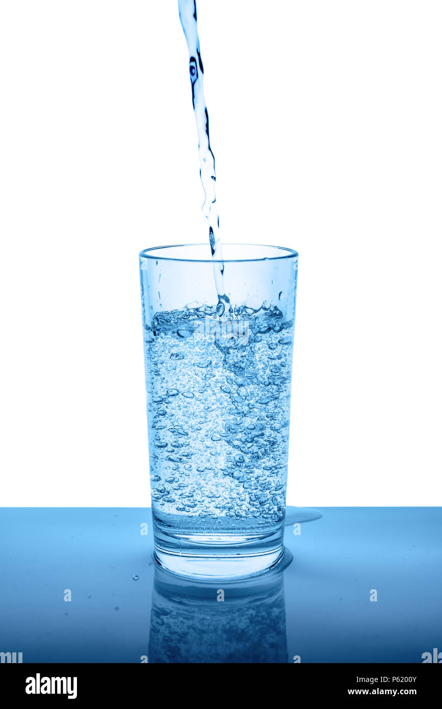 pouring mineral water in transparent glass with drops and bubbles ...
