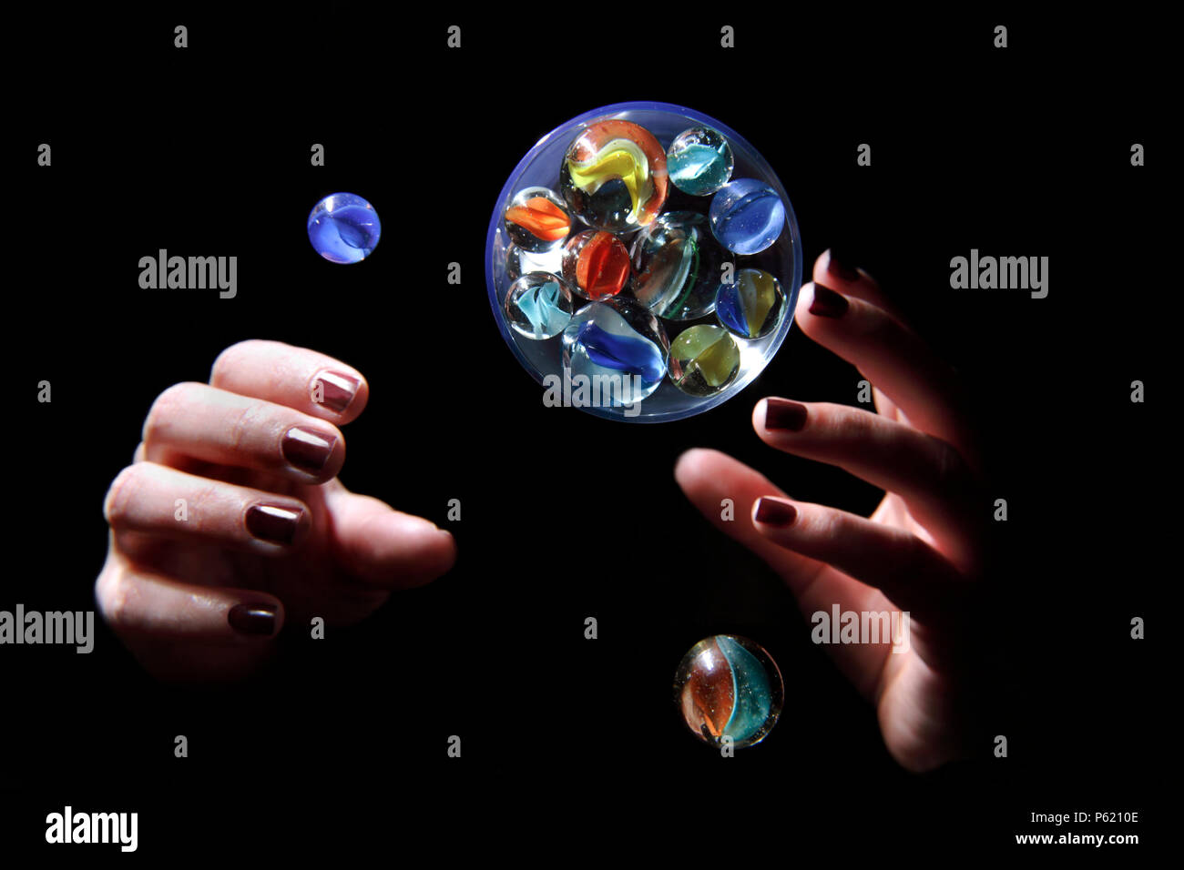A pair of hands cluches at a group of marbles Stock Photo - Alamy