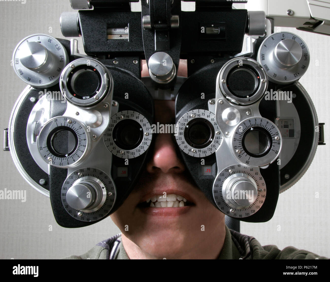 A person having an eye examination, behind an optometrist's machine ...