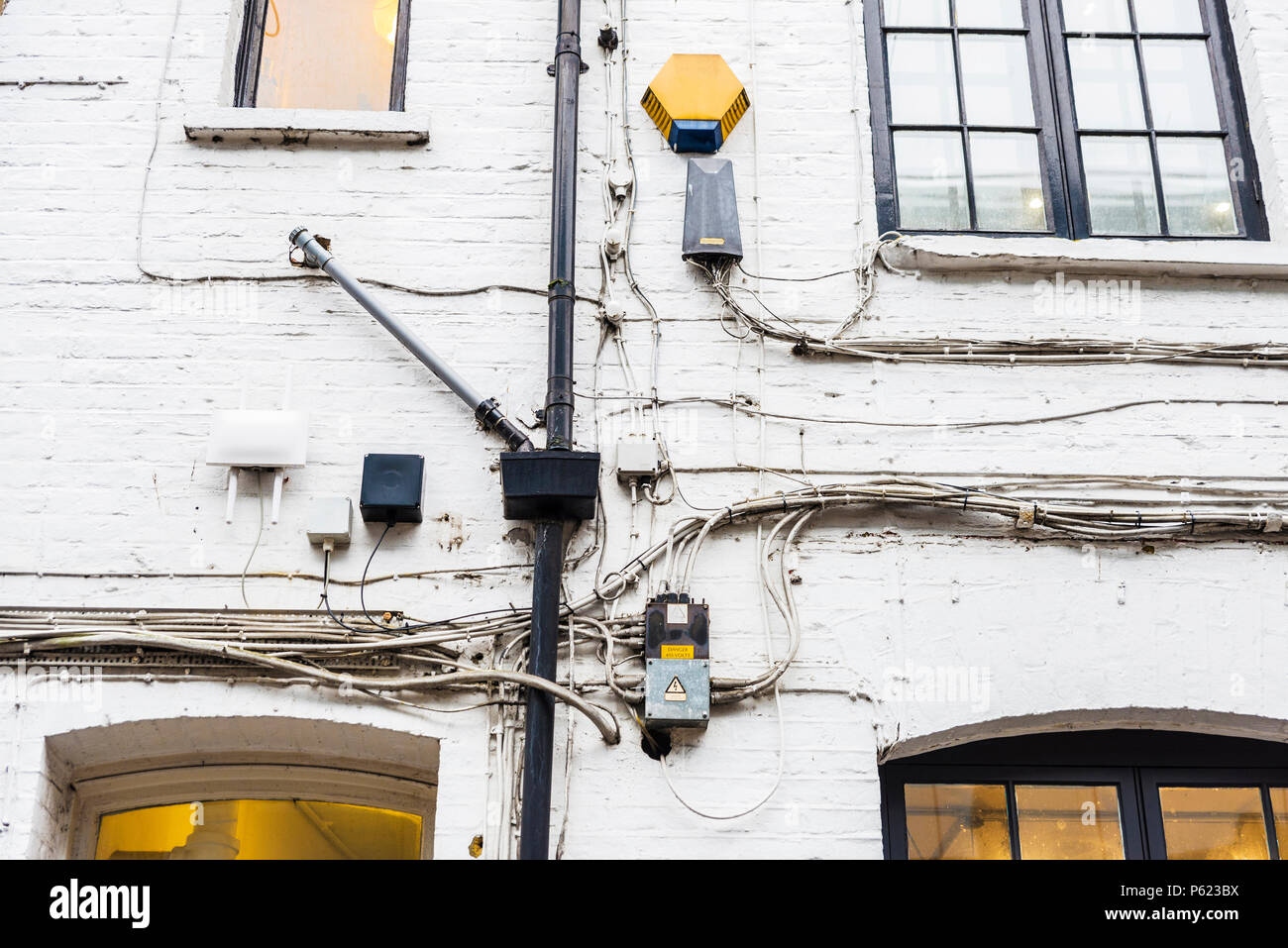 Heap of power cables, communications and alarm on an old white brick ...