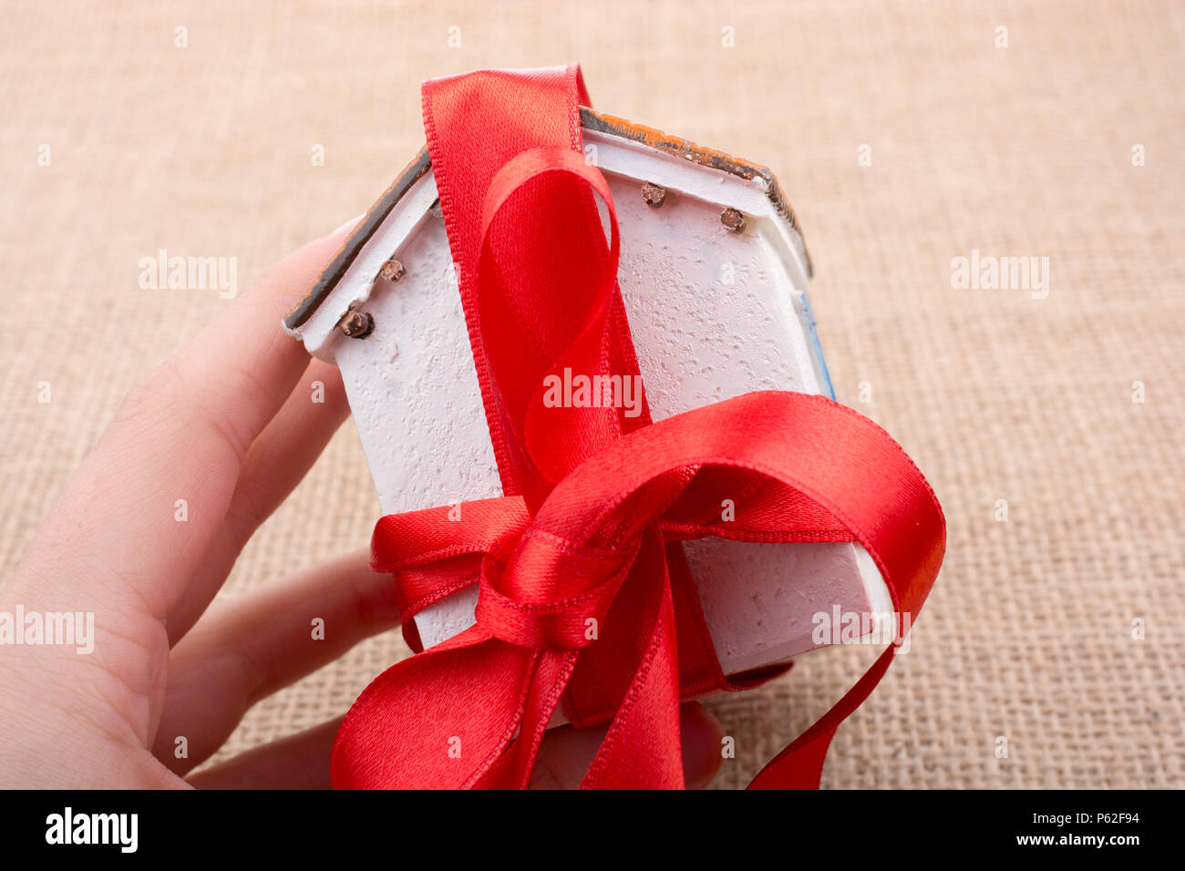 Little model house wrapped in red ribbon on a canvas Stock Photo - Alamy