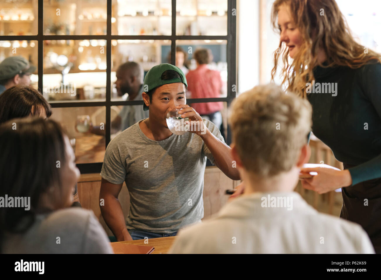 Diverse group of friends ordering food from a bistro waitress Stock ...