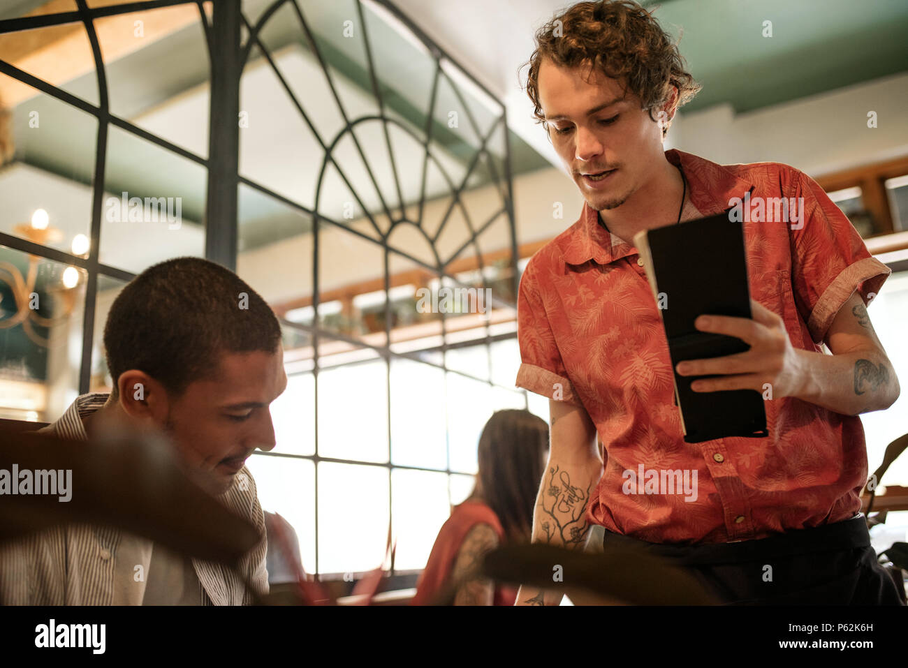 Waiter explaining the menu to a smiling restaurant customer Stock Photo ...