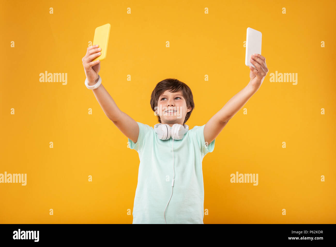Exuberant schoolboy having two phones Stock Photo - Alamy