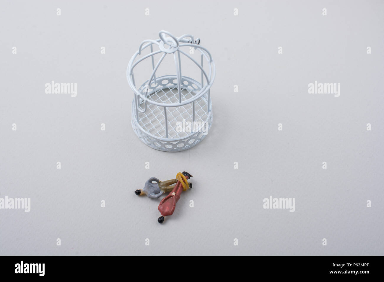 Tiny figurine of men wrapped in rope beside a cage Stock Photo - Alamy