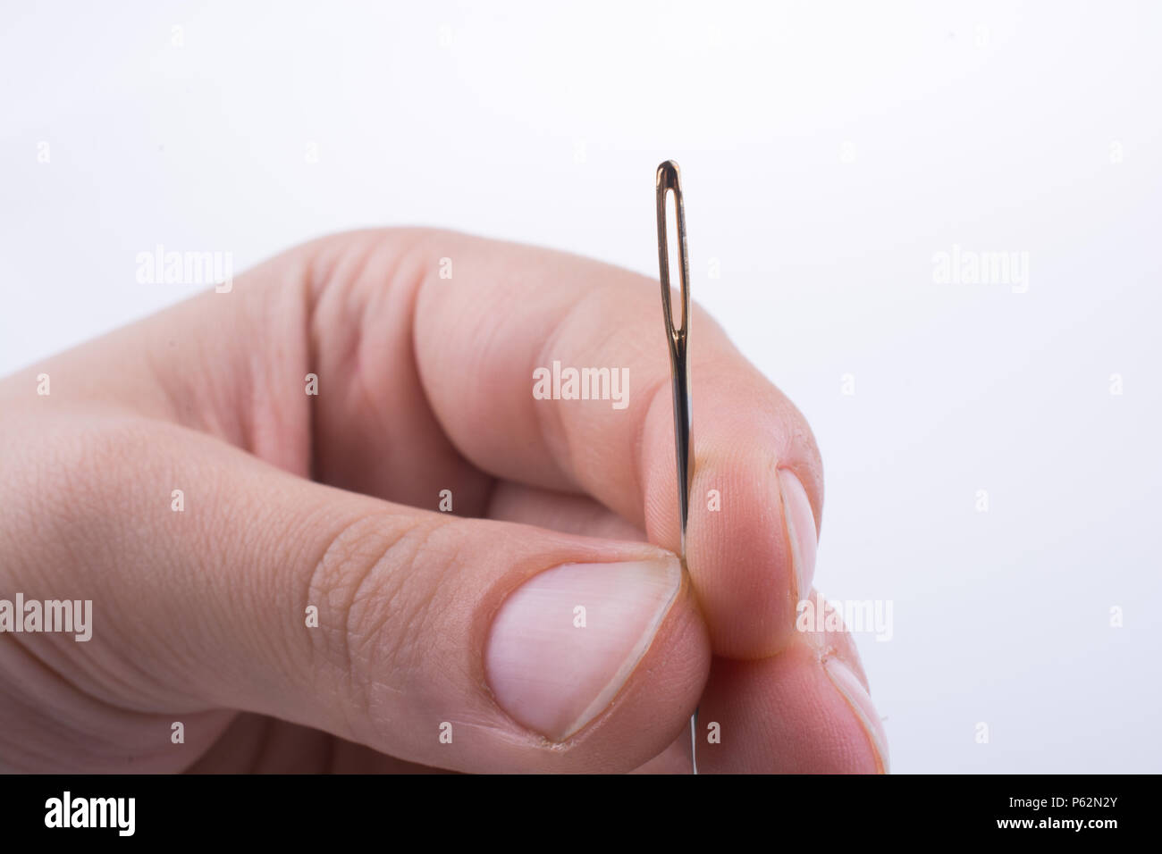 Hand holding a needle on a white background Stock Photo - Alamy