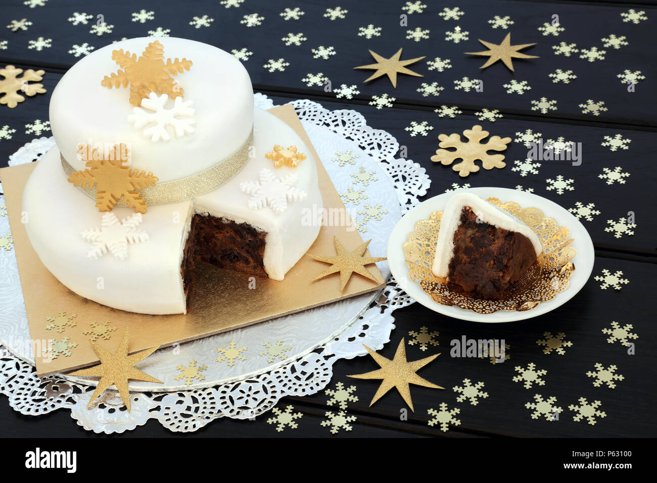 Christmas cake with two tiered iced layers and slice on a plate with ...