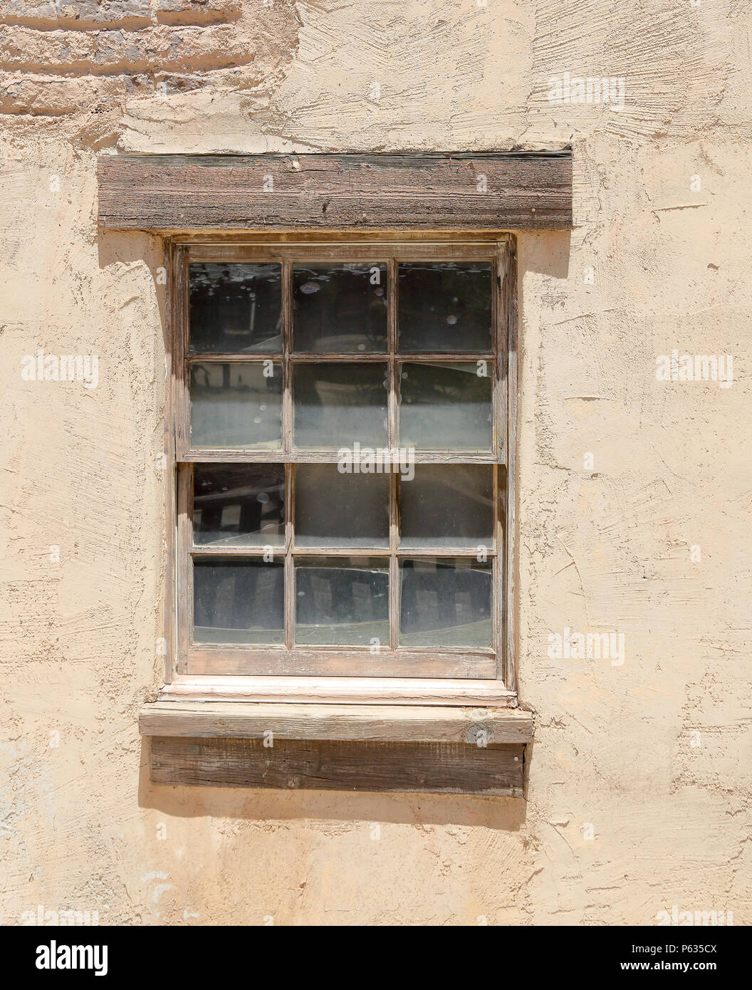 Old wood framed window with twelve glass panes, set in an adobe wall ...