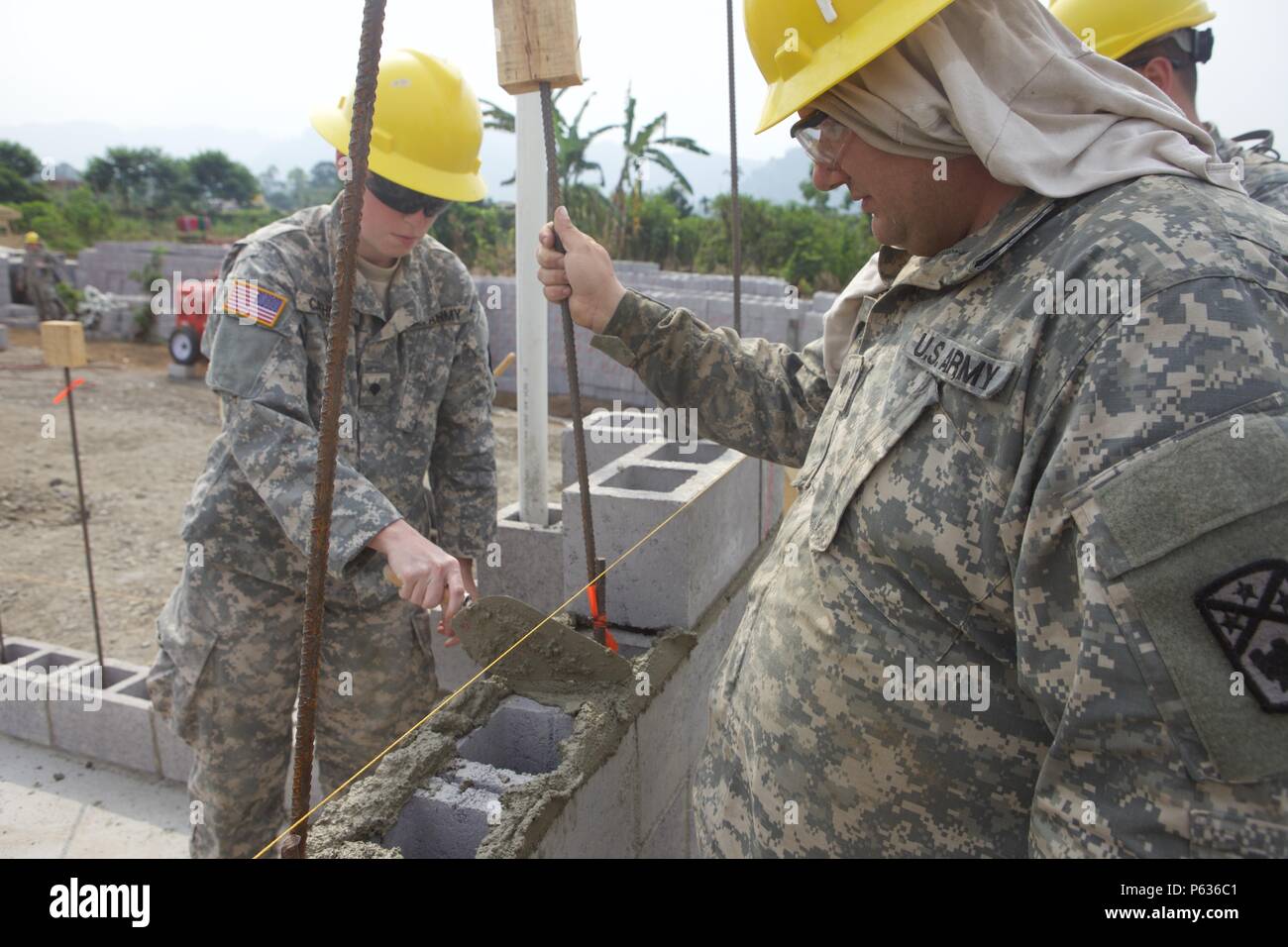 U.S. Army Spc. Daniel Rayburn and Spc. Karin Cathey lay down cement to ...