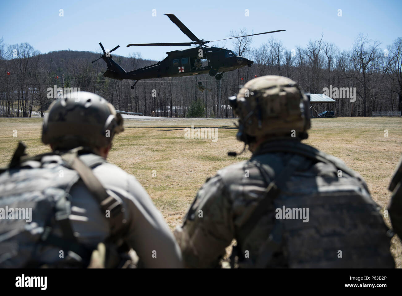 U.S. Soldiers stand ready as a medic descends from an HH-60M MEDEVAC ...
