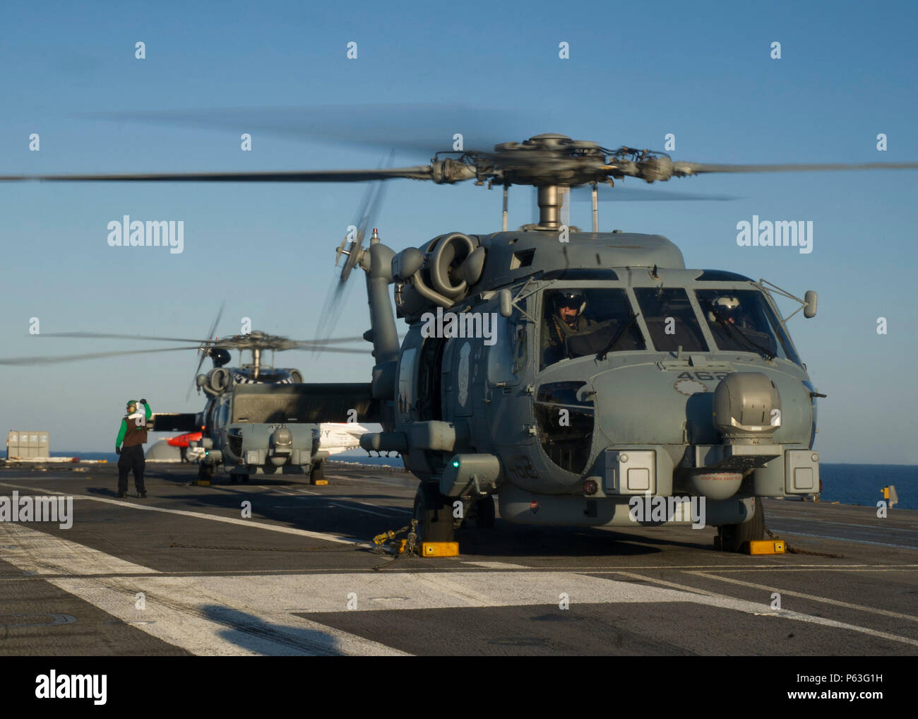 Two MH-60R Seahawk helicopters prepare for launch from the flight deck ...