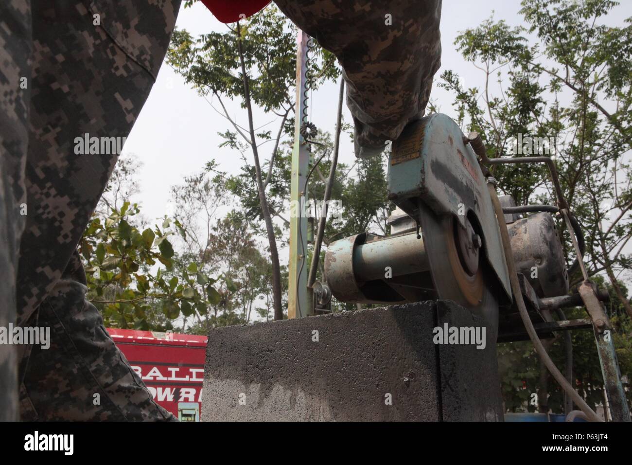 U.S. Army Spc. Cory Smith of the 994th Engineer Company uses wet saw to ...