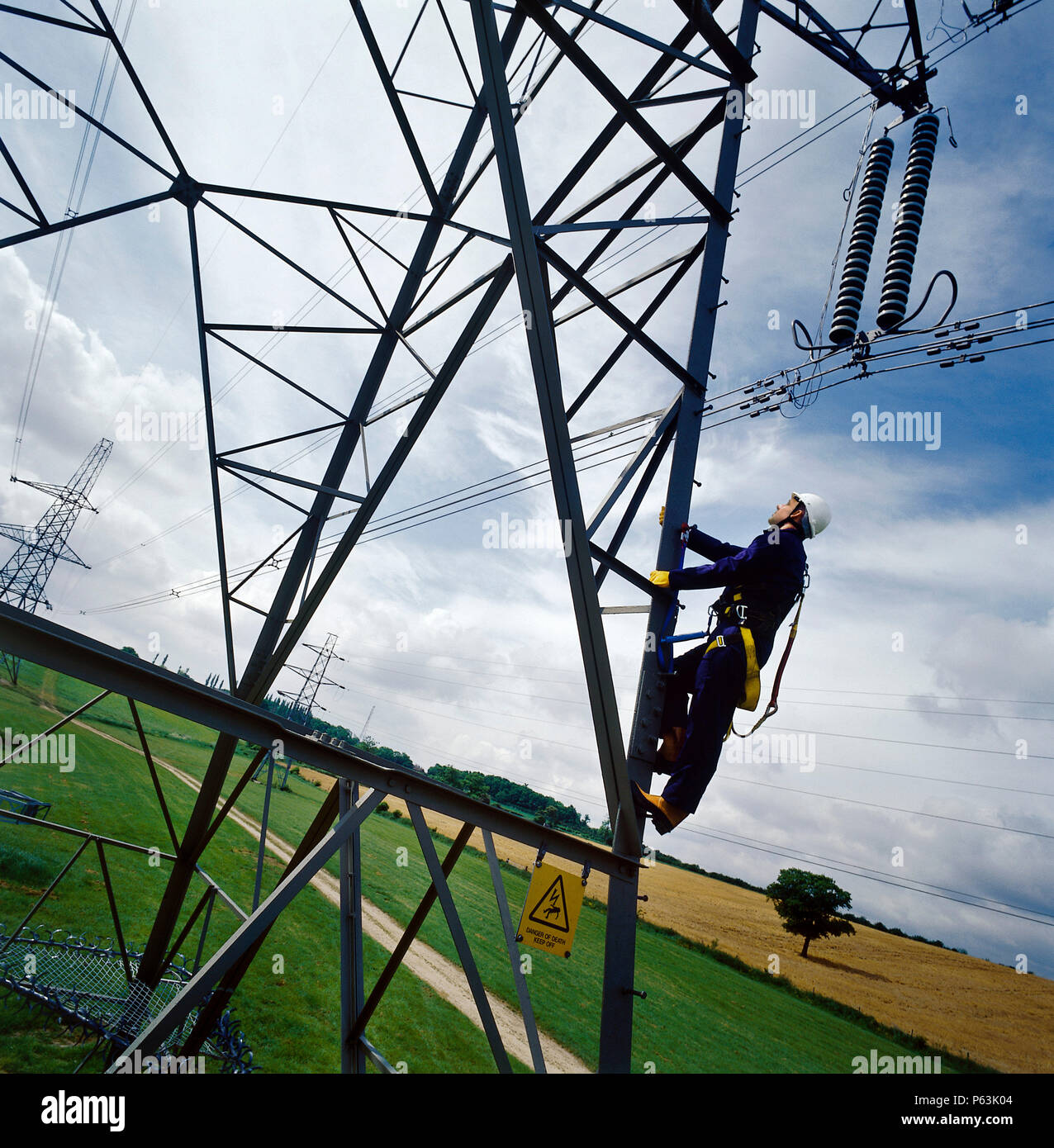 Worker climbing electricity pylon Stock Photo - Alamy