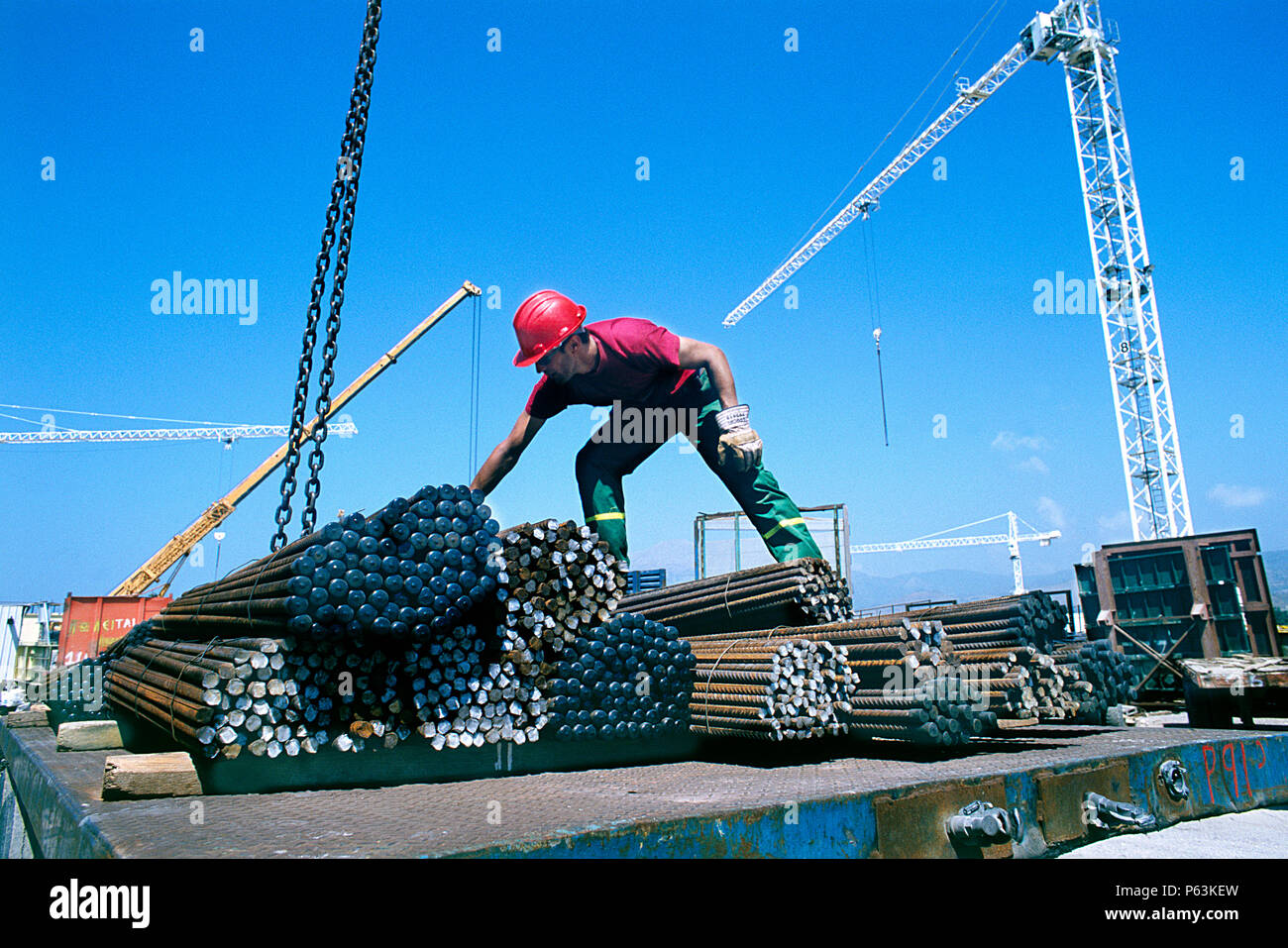 Unloading steel reinforcement bundle from lorry by crane on a ...