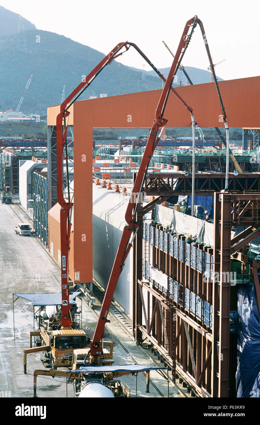 Concrete pumps swing their booms over to the top section of giant ...