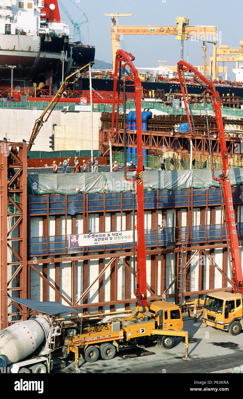 Concrete pumps swing their booms over to the top section of giant ...