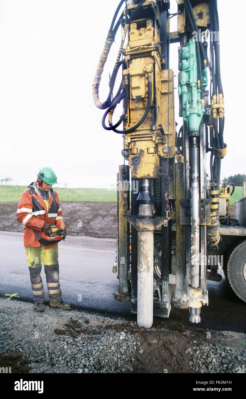 Safety barrier posts are fitted along the road side using a lorry ...