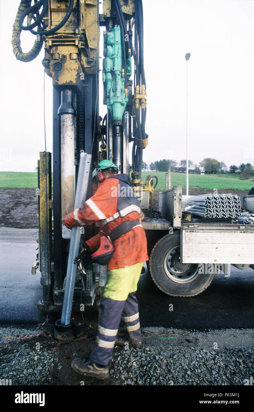 Safety barrier posts are fitted along the road side using a lorry ...