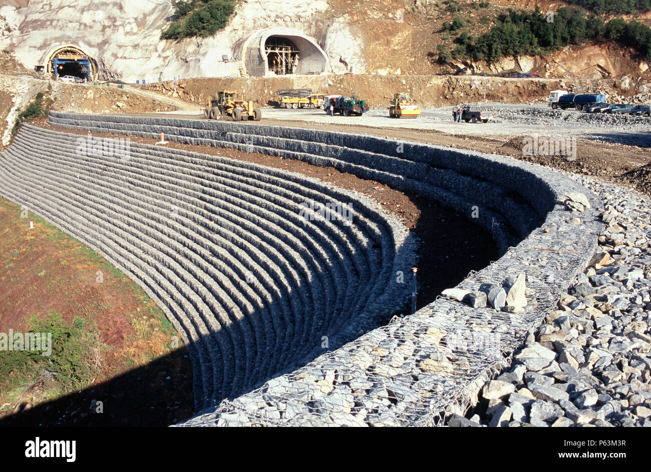 A scraper levels crushed rock fill for a gabion faced stepped ...