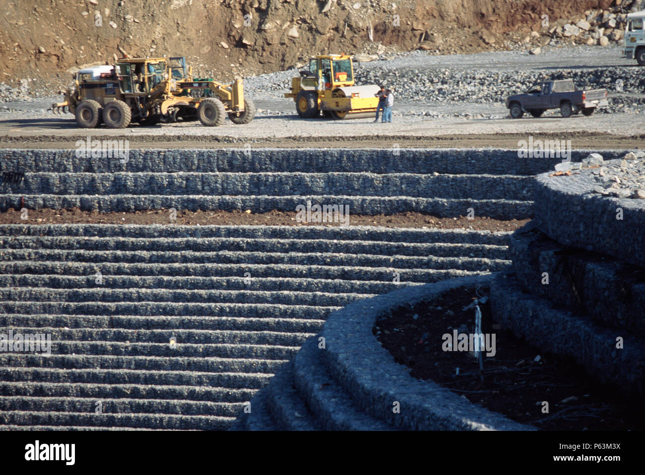 A scraper levels crushed rock fill for a gabion faced stepped ...