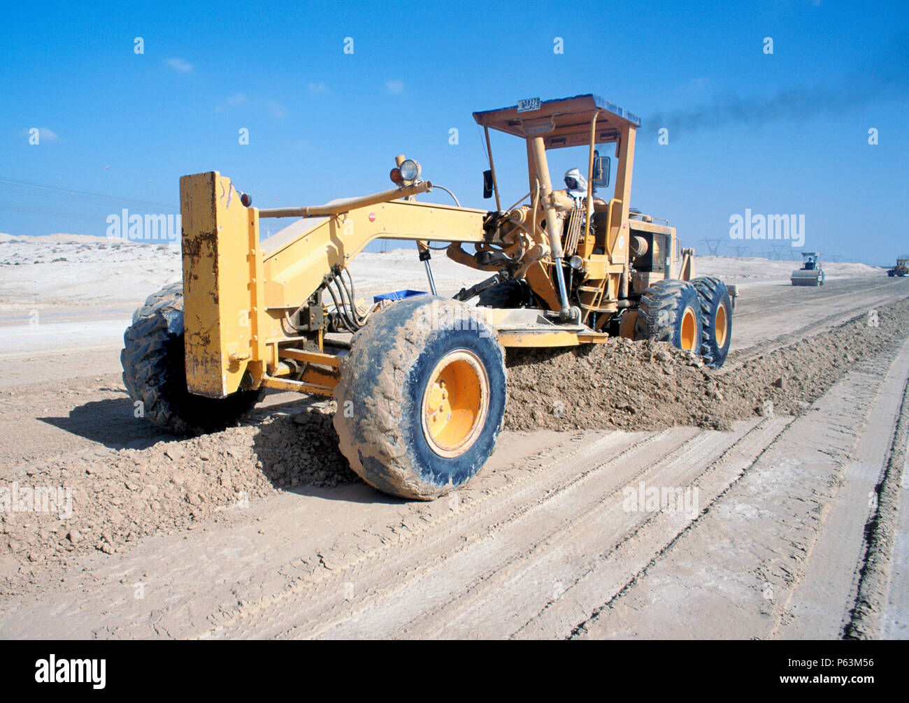 A grader levels the desert ground for road base and later asphalting ...