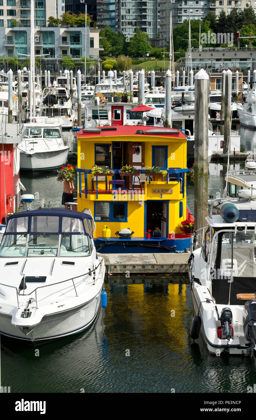 Colourful yellow houseboat and other boats in Coal Harbour Marina ...