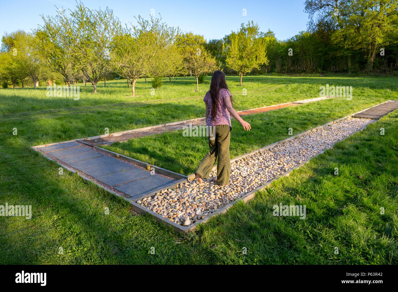 Woman walking on a barefoot track or trail on the afternoon sunlight ...