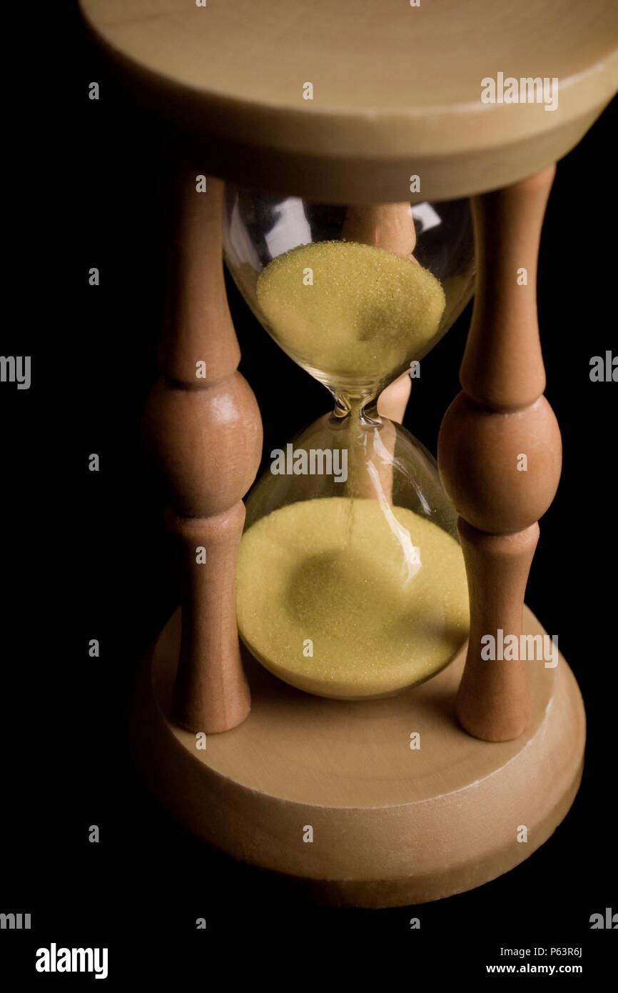 sand clock showing how is time passing on black background Stock Photo ...