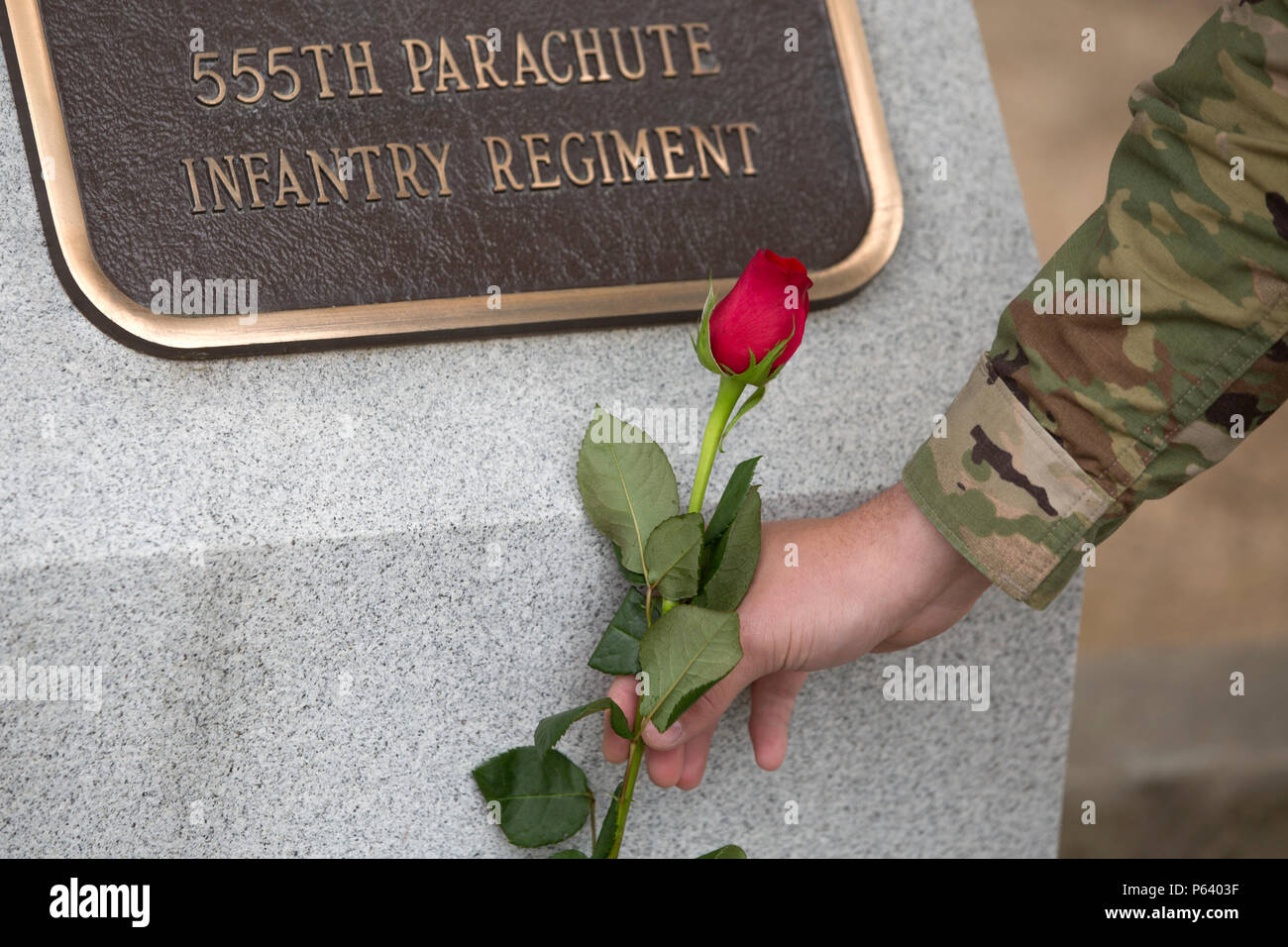 A U.S. Army paratrooper places a rose on a memorial before the wreath ...