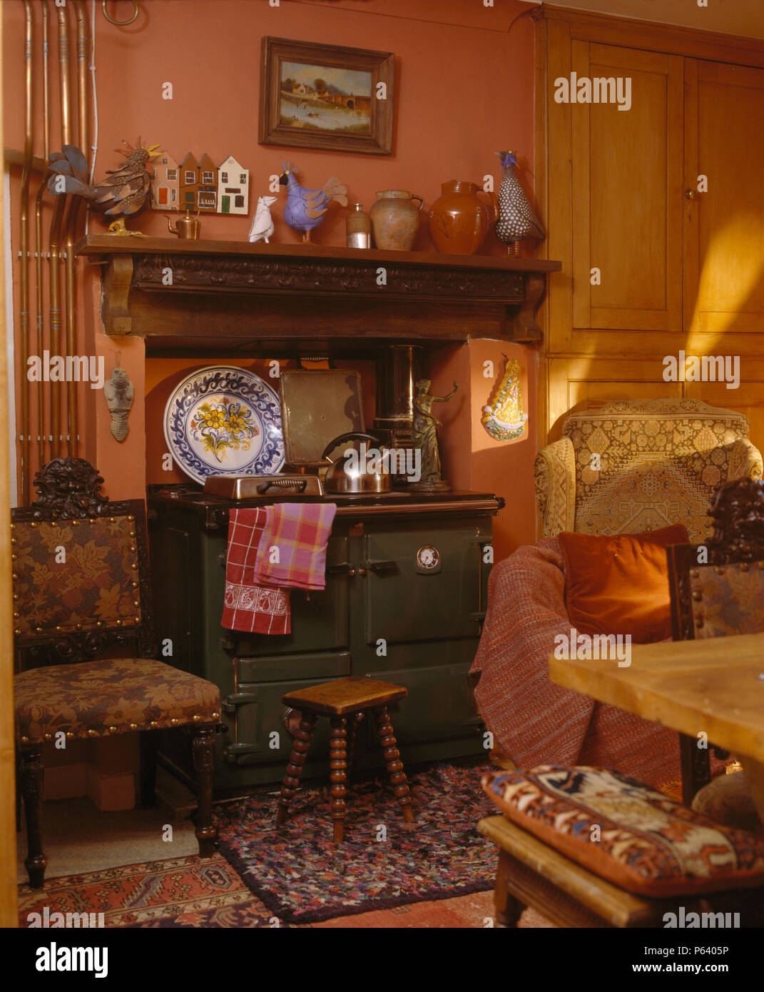 Jugs and ornaments on shelf above green Aga in country kitchen with ...