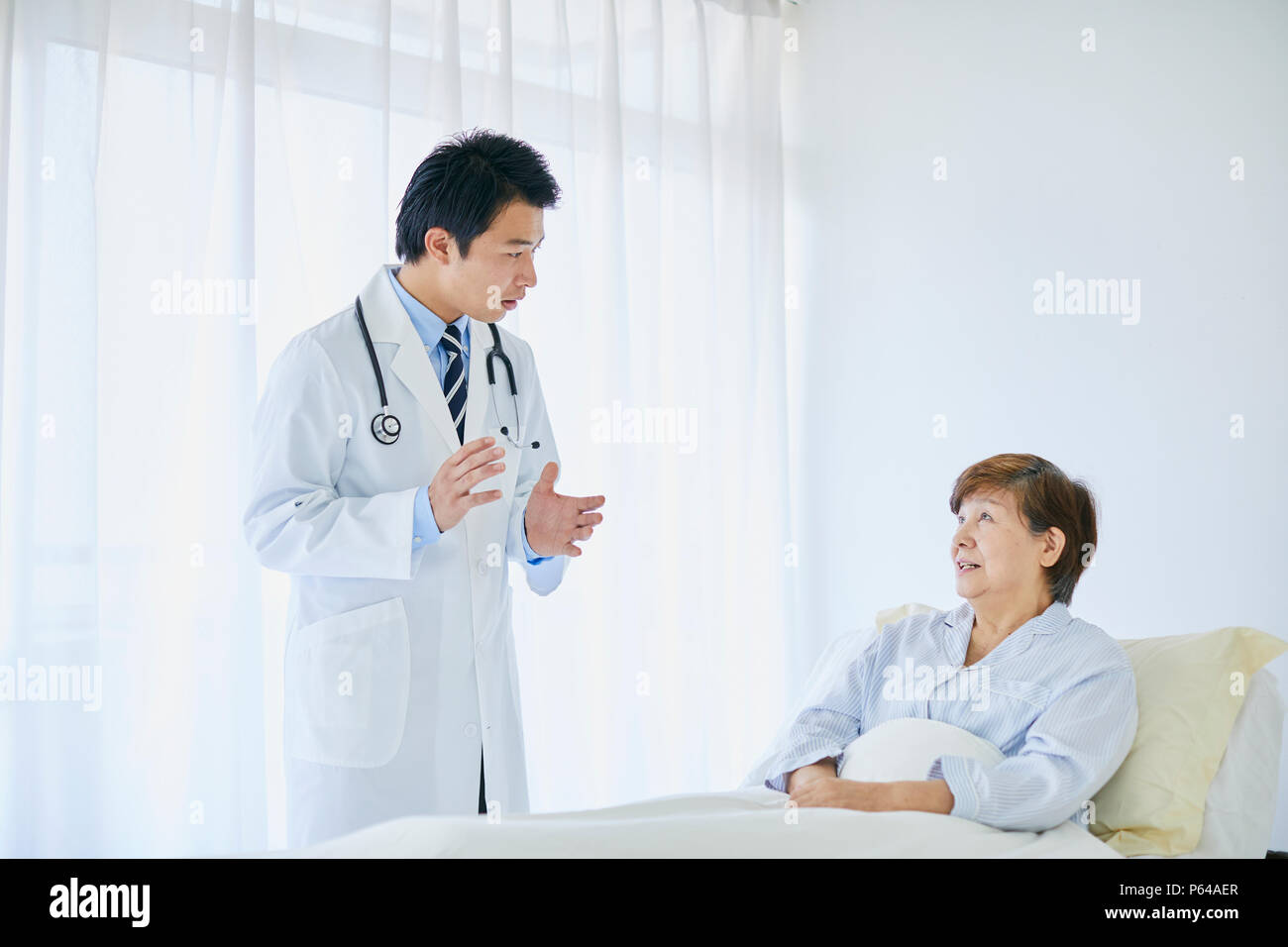 Japanese doctor with a patient in bed Stock Photo - Alamy