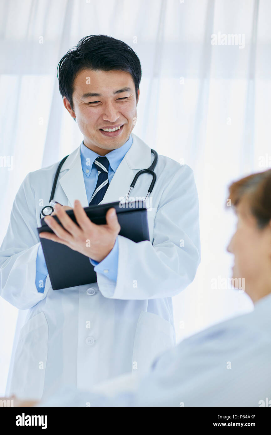 Japanese doctor with a patient in bed Stock Photo - Alamy