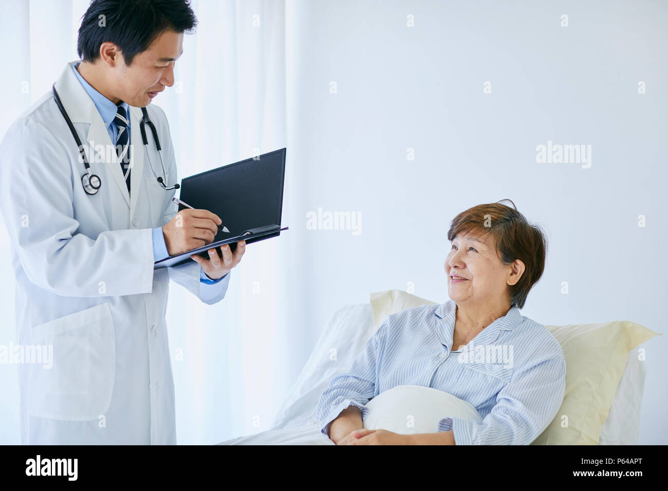 Japanese doctor with a patient in bed Stock Photo - Alamy