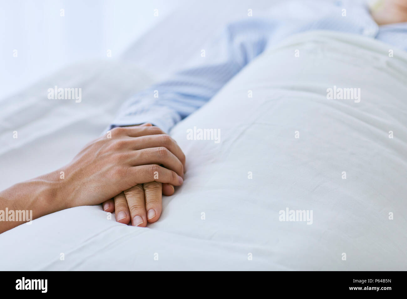 Holding hand of patient in bed Stock Photo - Alamy