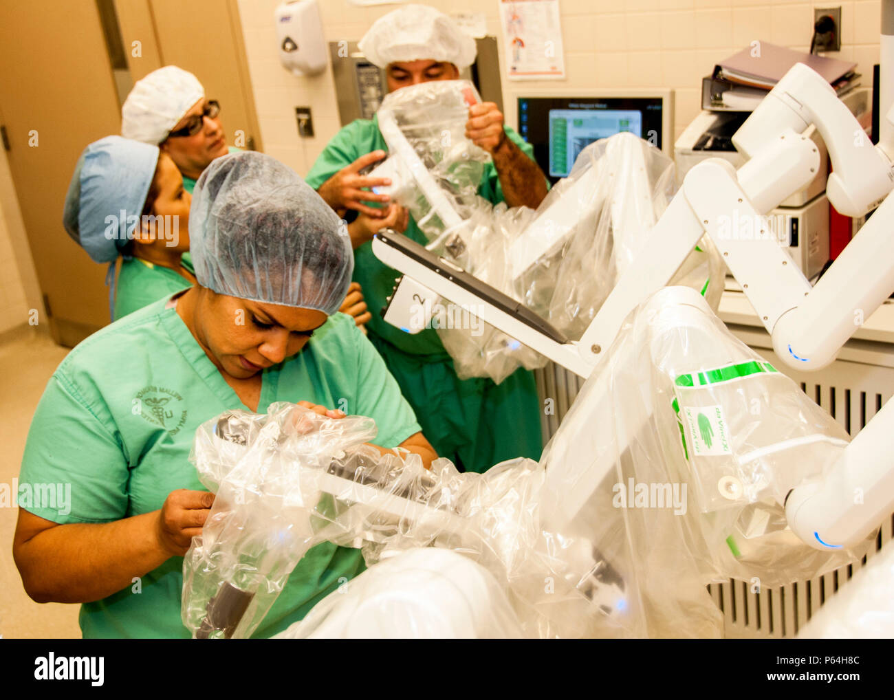 Medical personnel place sterilized covers on the arms of the daVinci Xi ...