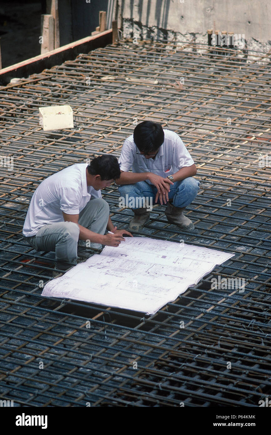 Site engineers looking a plans on a construction site in Singapore ...