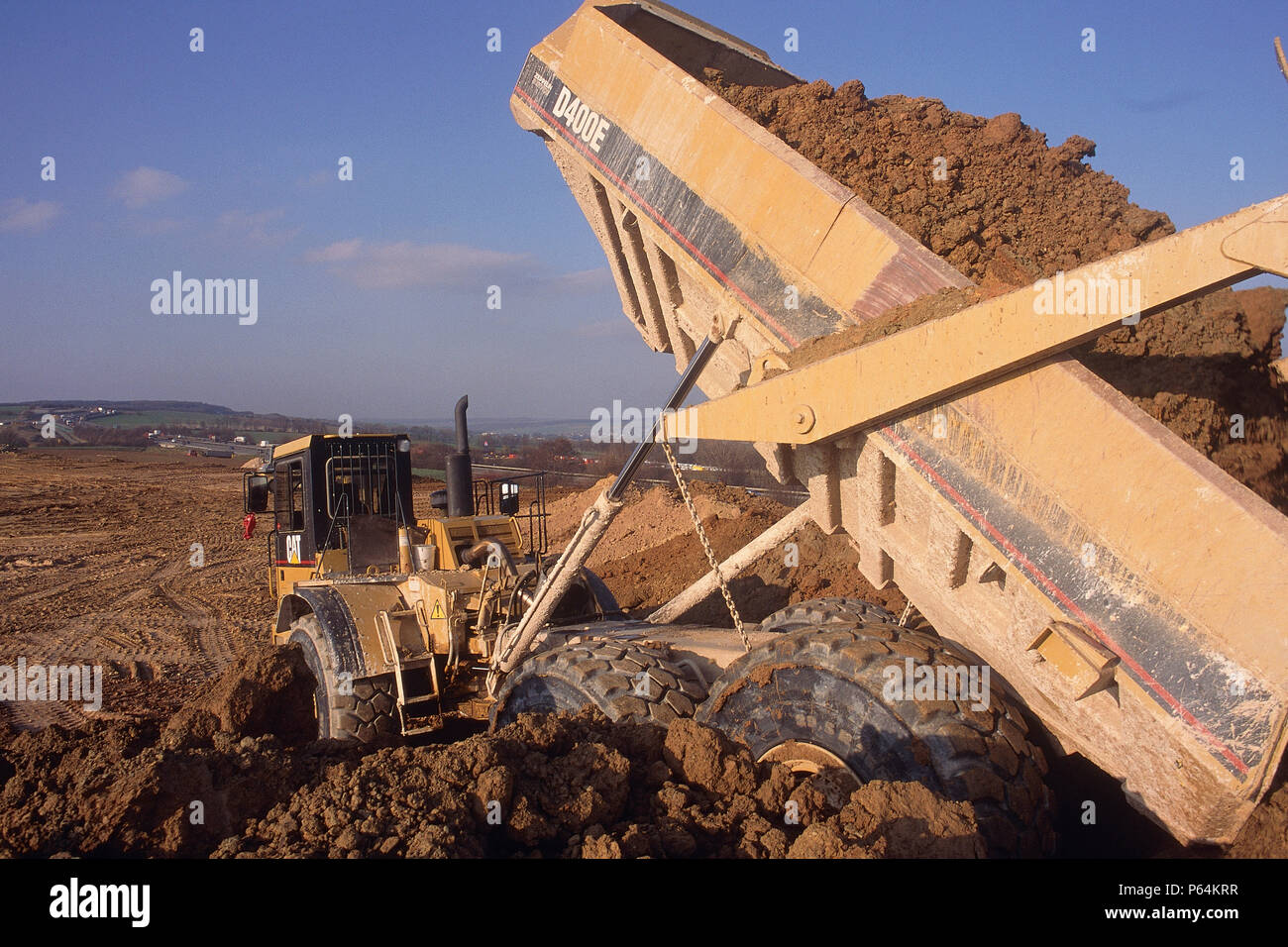 Caterpillar D400E articulated dumper truck placing fill to embankment ...
