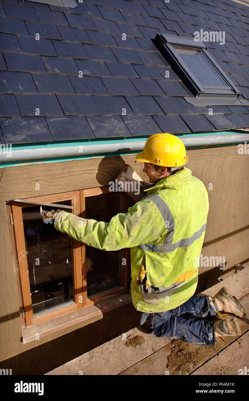 A plasterer rendering a roughcast finish around new hardwood casement ...