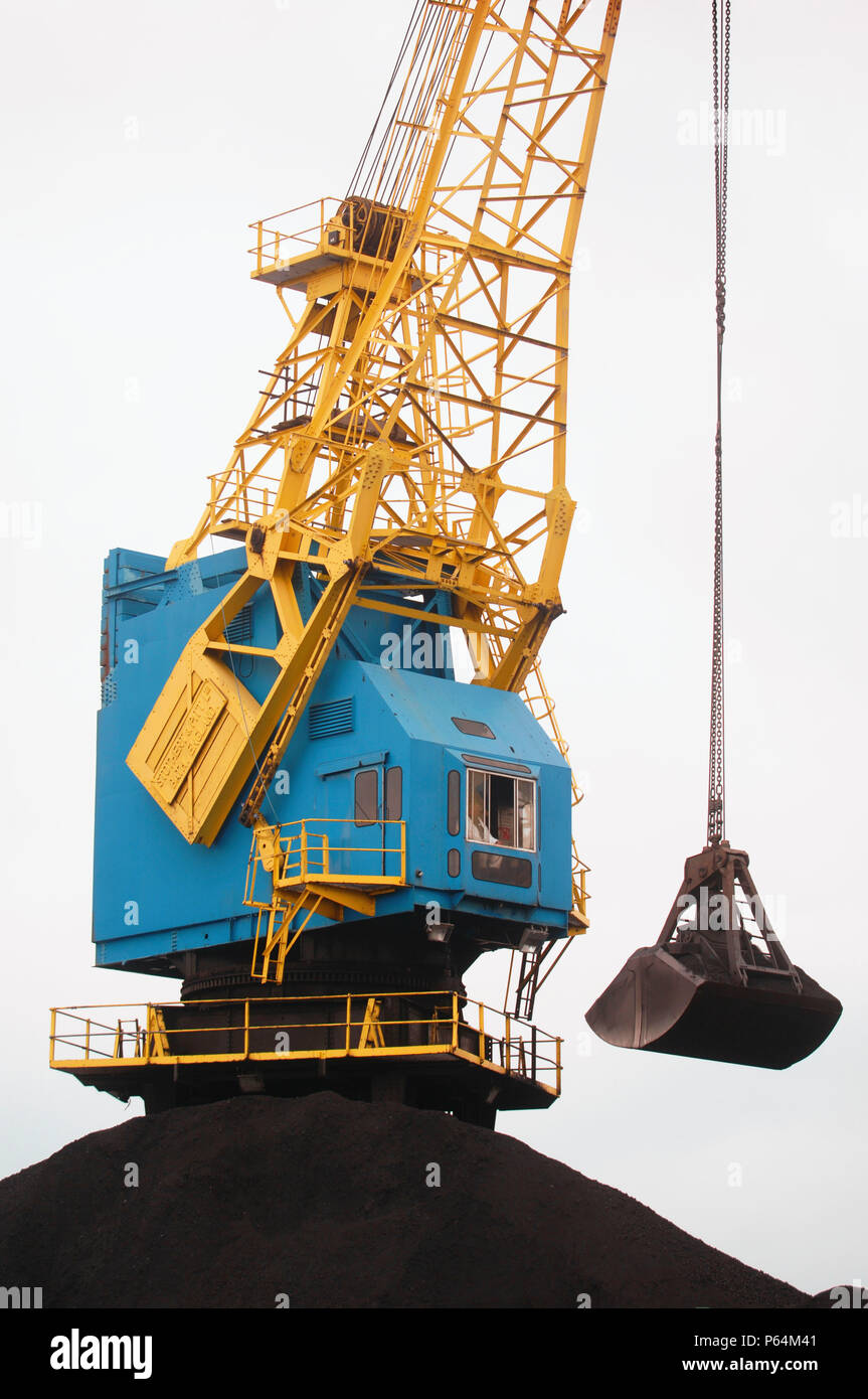 Crane unloading coal from a container ship on the dockside at a port in ...