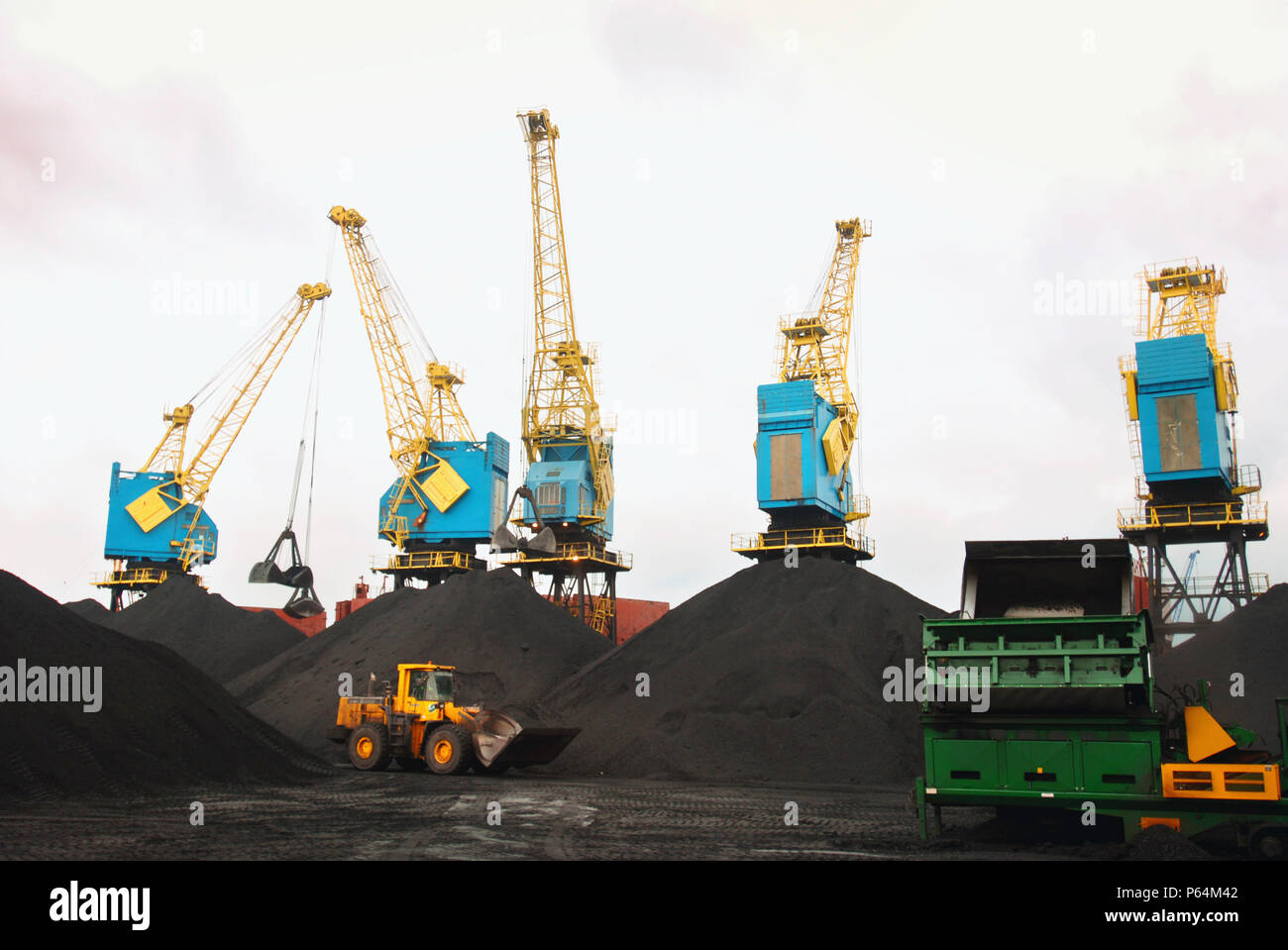 Crane unloading coal from a container ship on the dockside at a port in ...