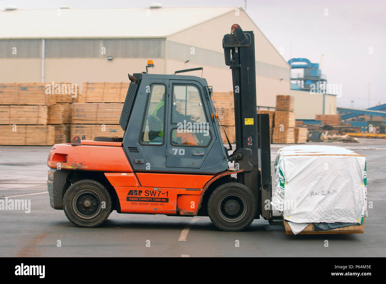 Forklift truck lifting timber on the dockside at a port in Newport ...