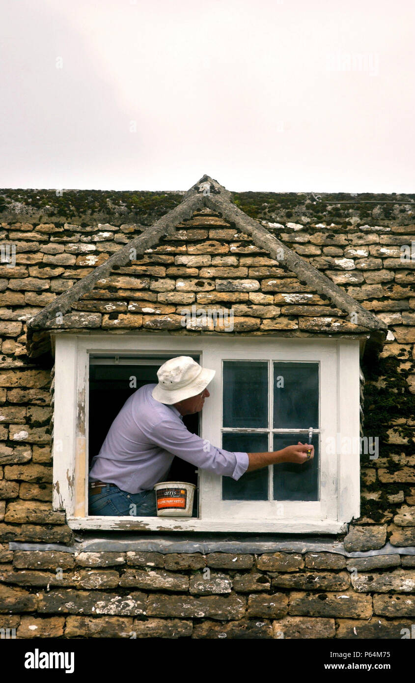 Painting the cottage dormer window, Gloucestershire, England Stock ...