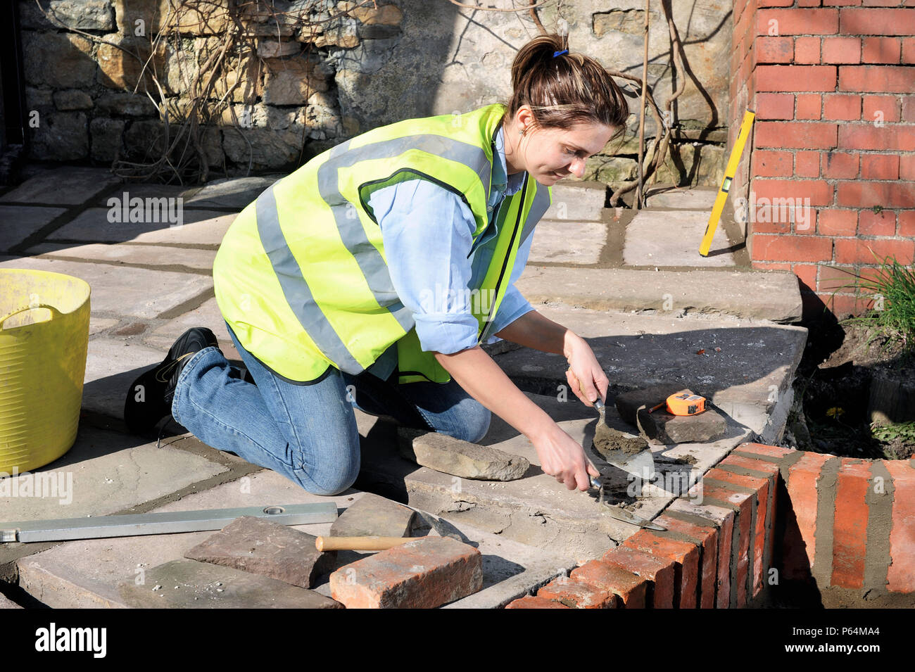 Woman laying patio at cottage under renovation, UK Stock Photo - Alamy