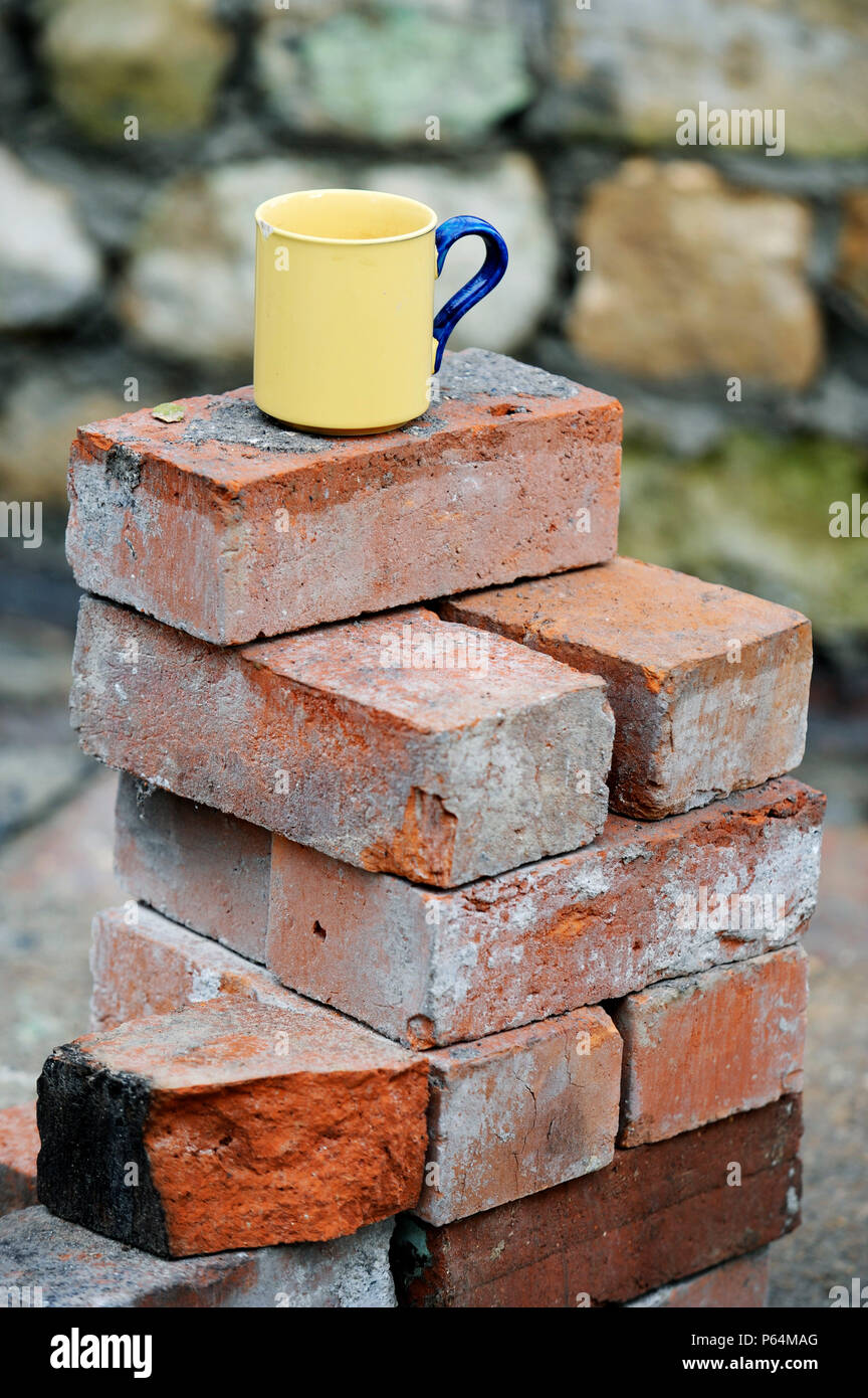 A builders mug of tea on a stack of reclaimed red bricks UK Stock Photo ...